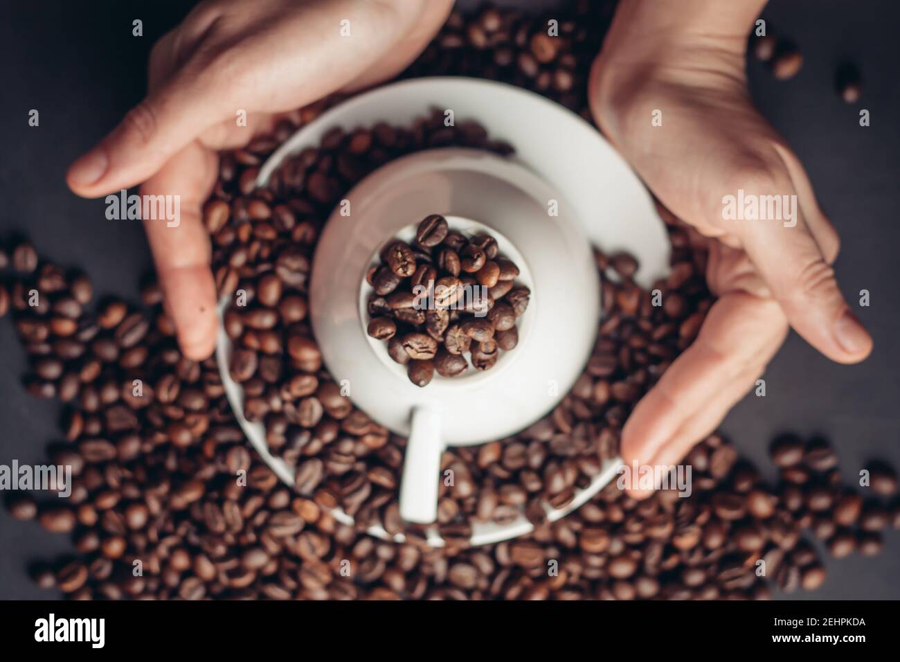 inverted white cup on a saucer and coffee beans on a gray table close ...