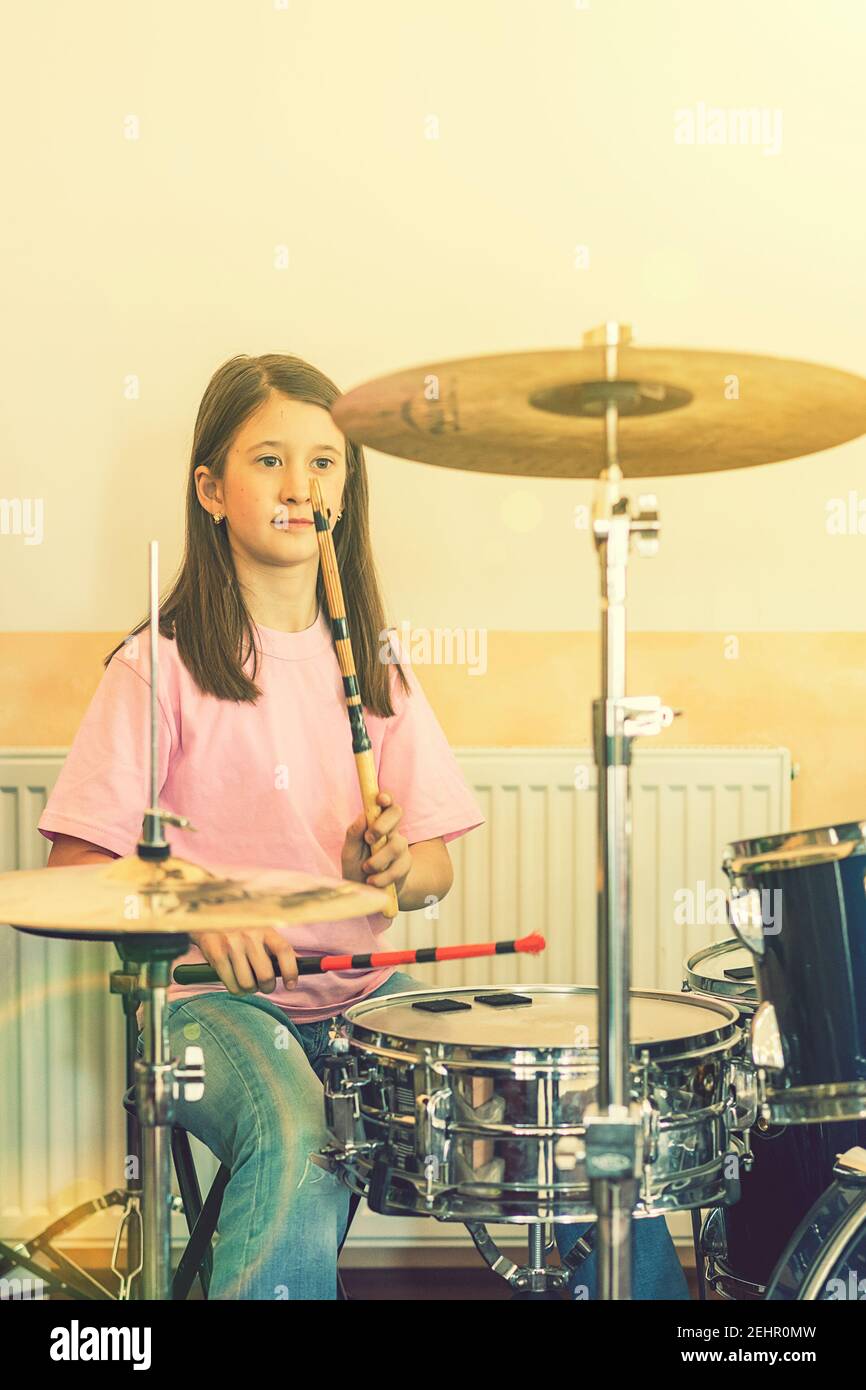 Happy girl in music therapy by playing drum kit on music room ...
