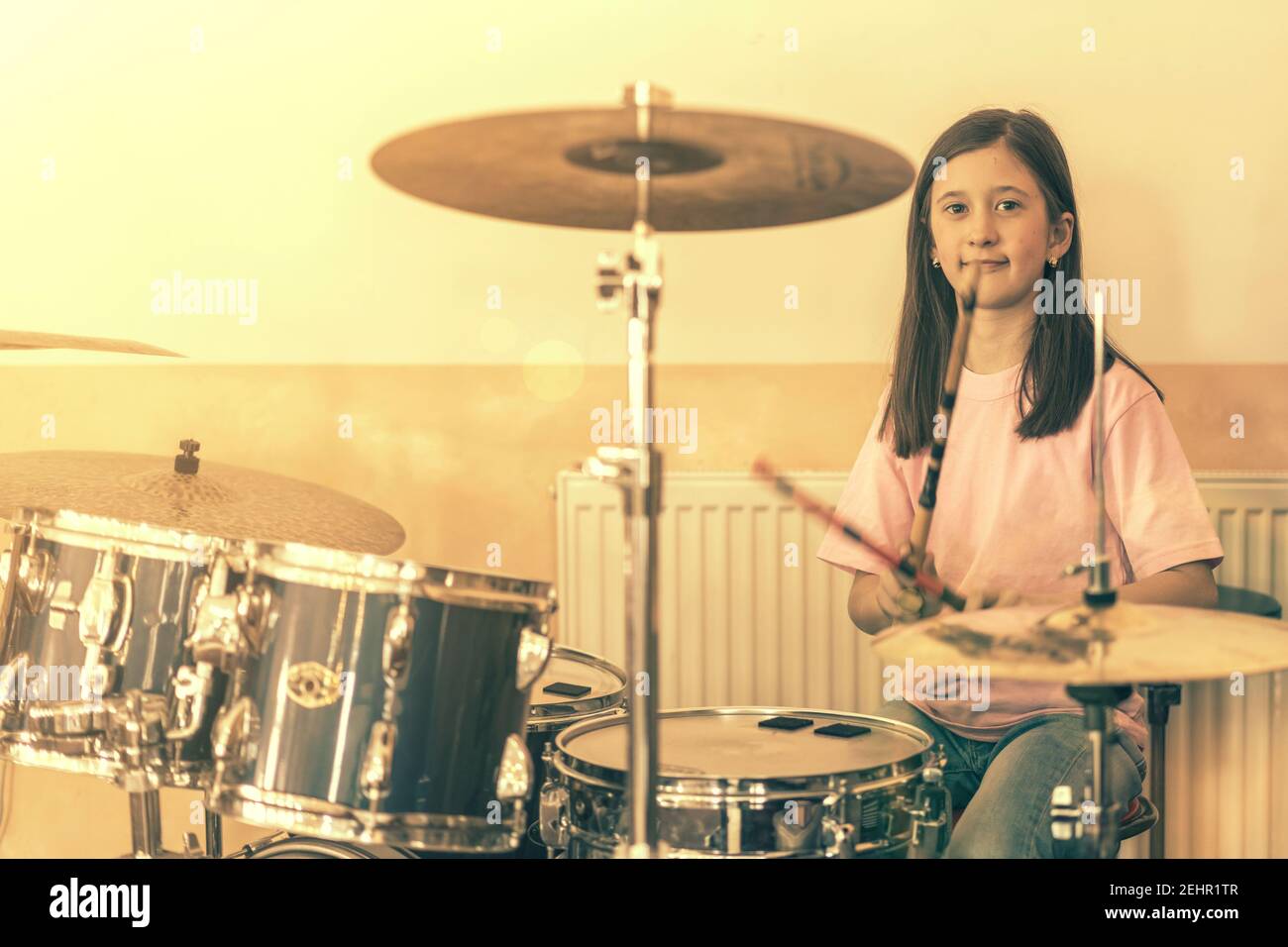 Happy girl in music therapy by playing drum kit on music room ...