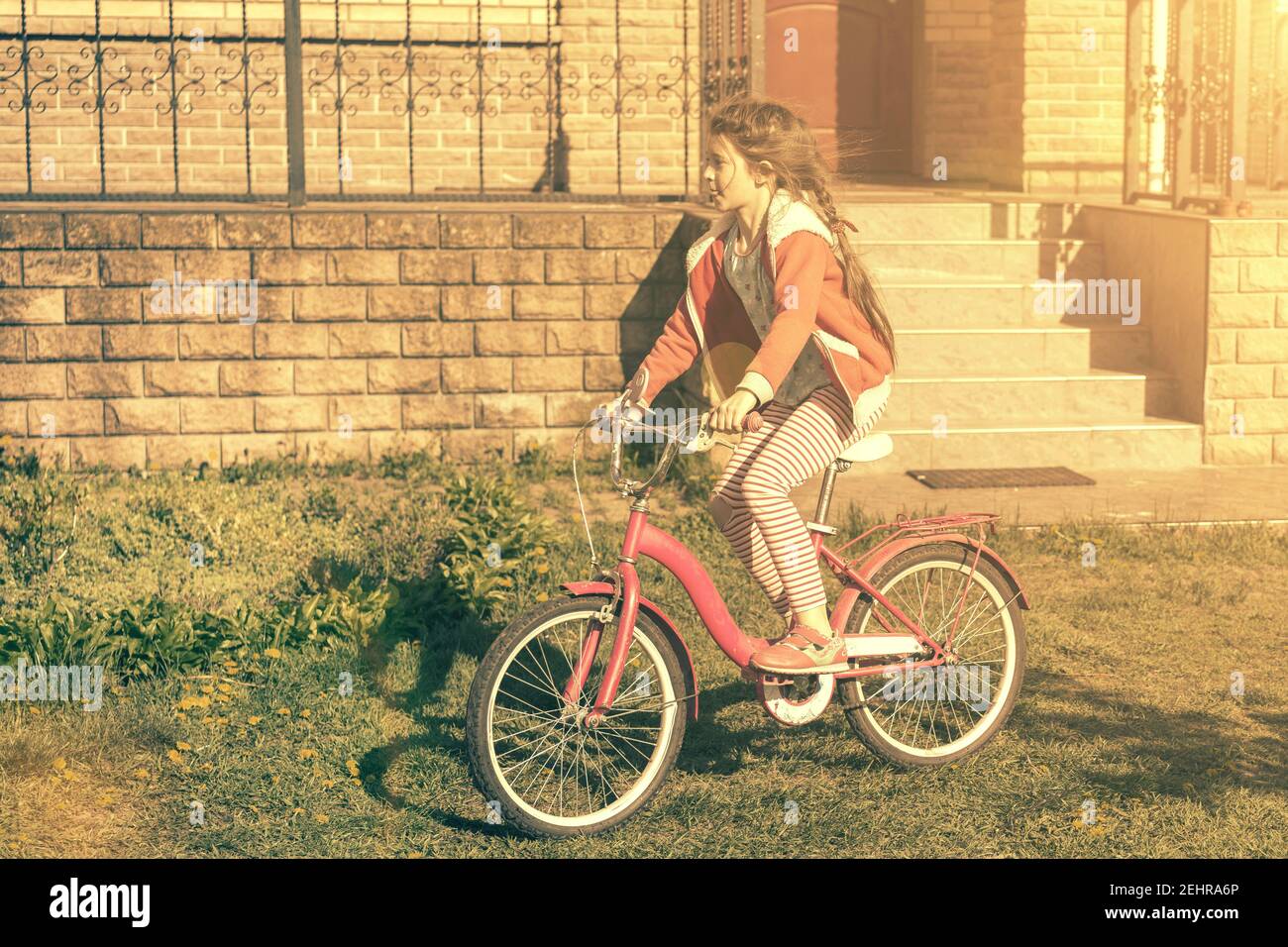 Girl riding a bike near the house. Girl on bicycle smiling while ride ...