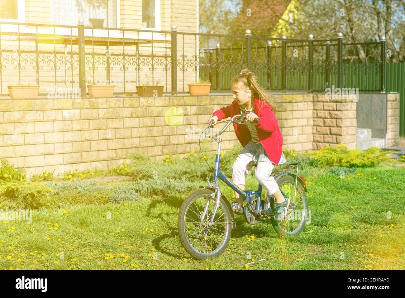 Girl riding a bike near the house. Girl on bicycle smiling while ride ...