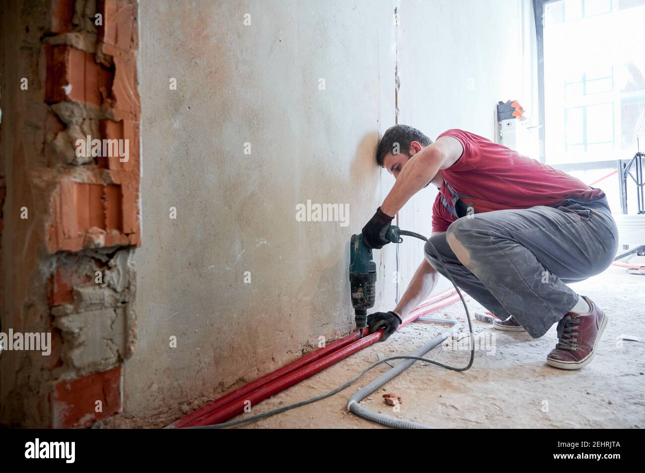 Side view snapshot of bearded plumber installing underfloor heating ...