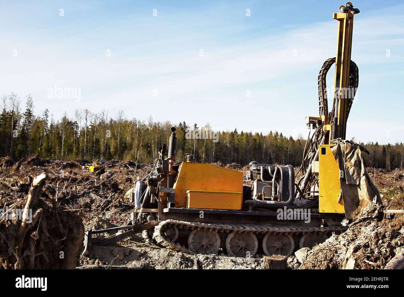 Mini-drilling rig on crawler track on site of sawn forest where large ...