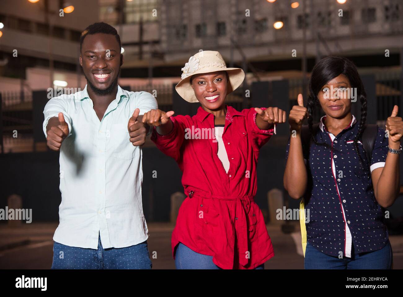 .group of young people standing outdoors doing thumb gesture while ...