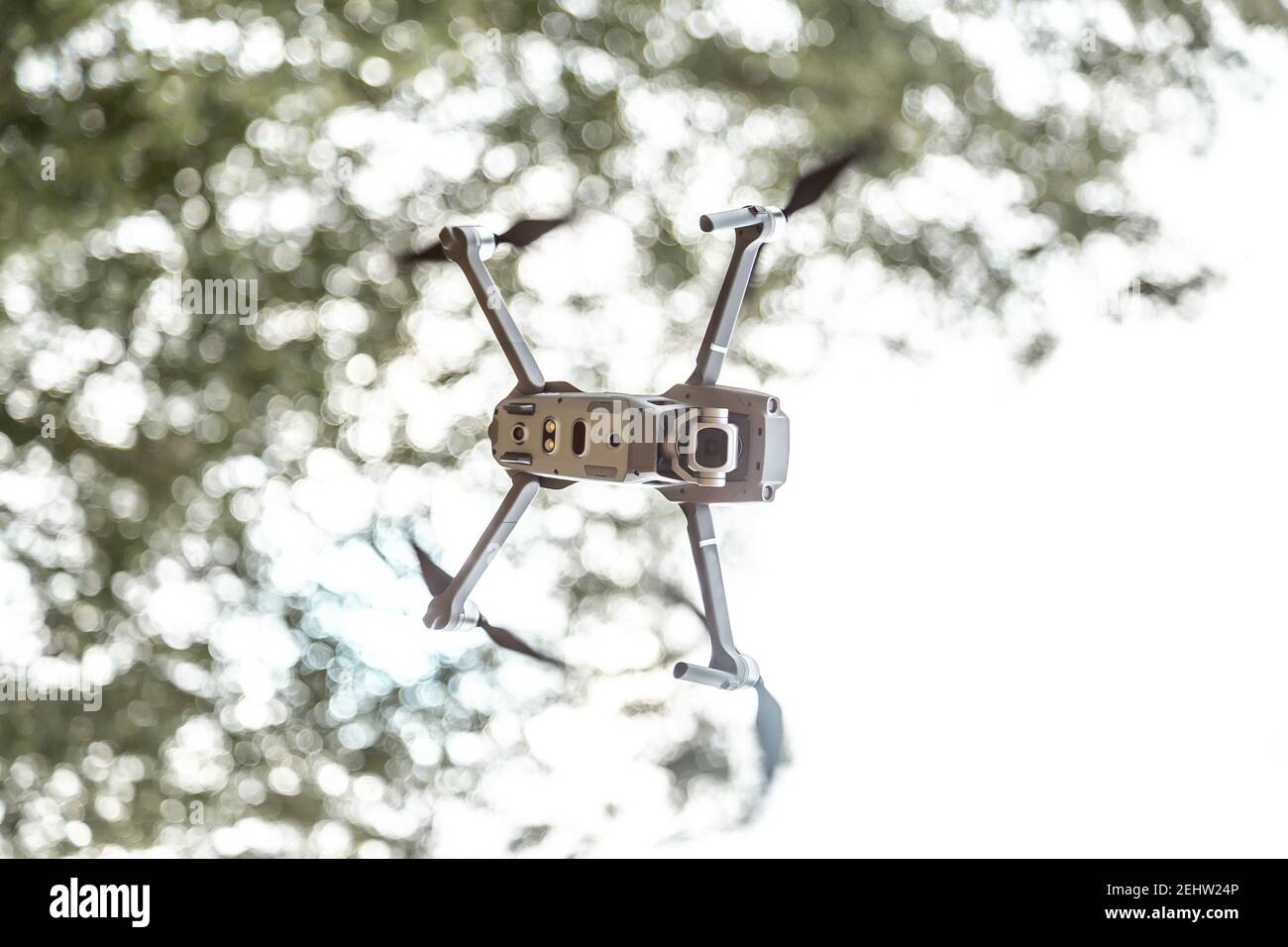 Closeup shot of a Silver matte drone with camera in the sky under the ...