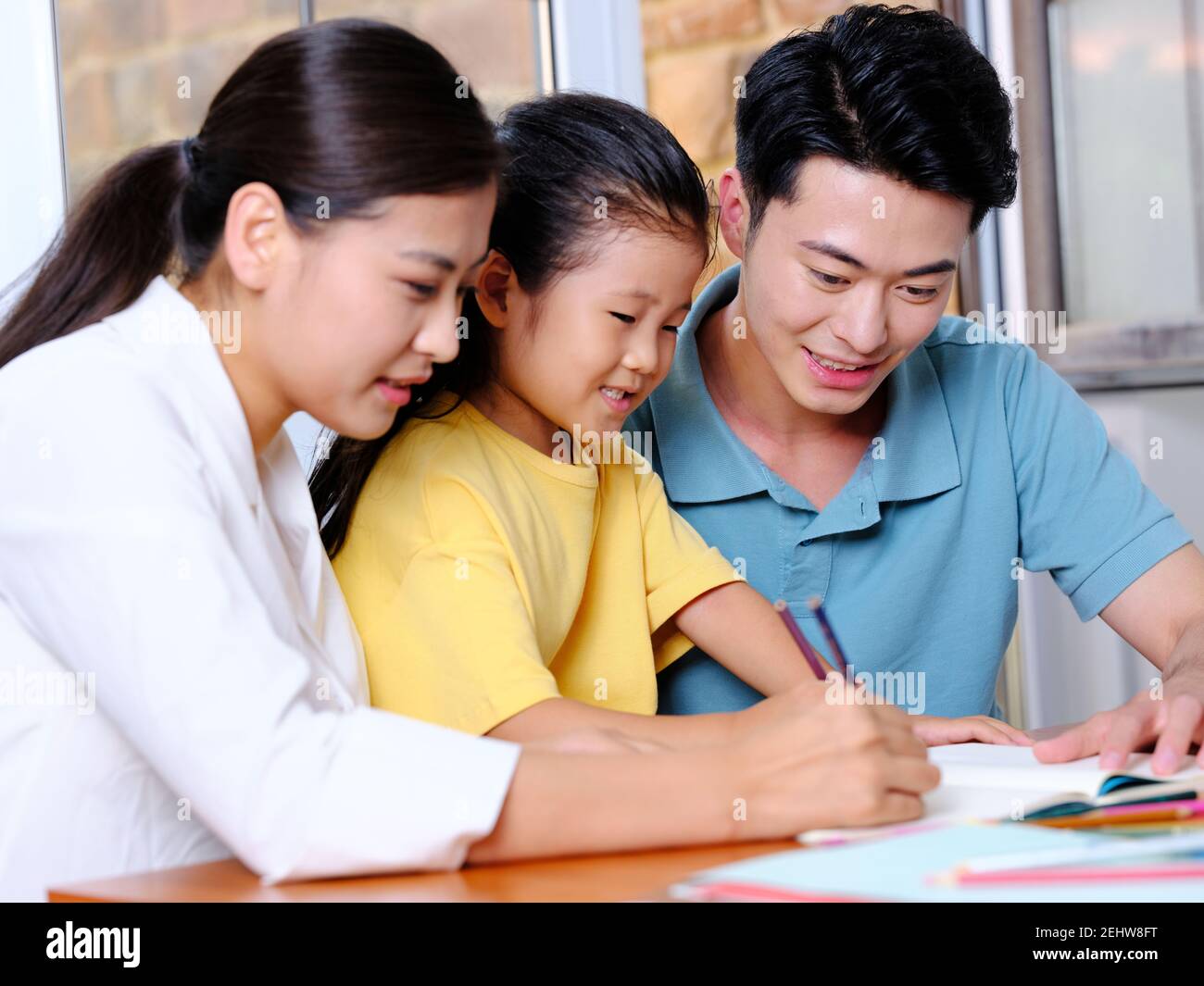 Happy family of three reading and writing together Stock Photo - Alamy