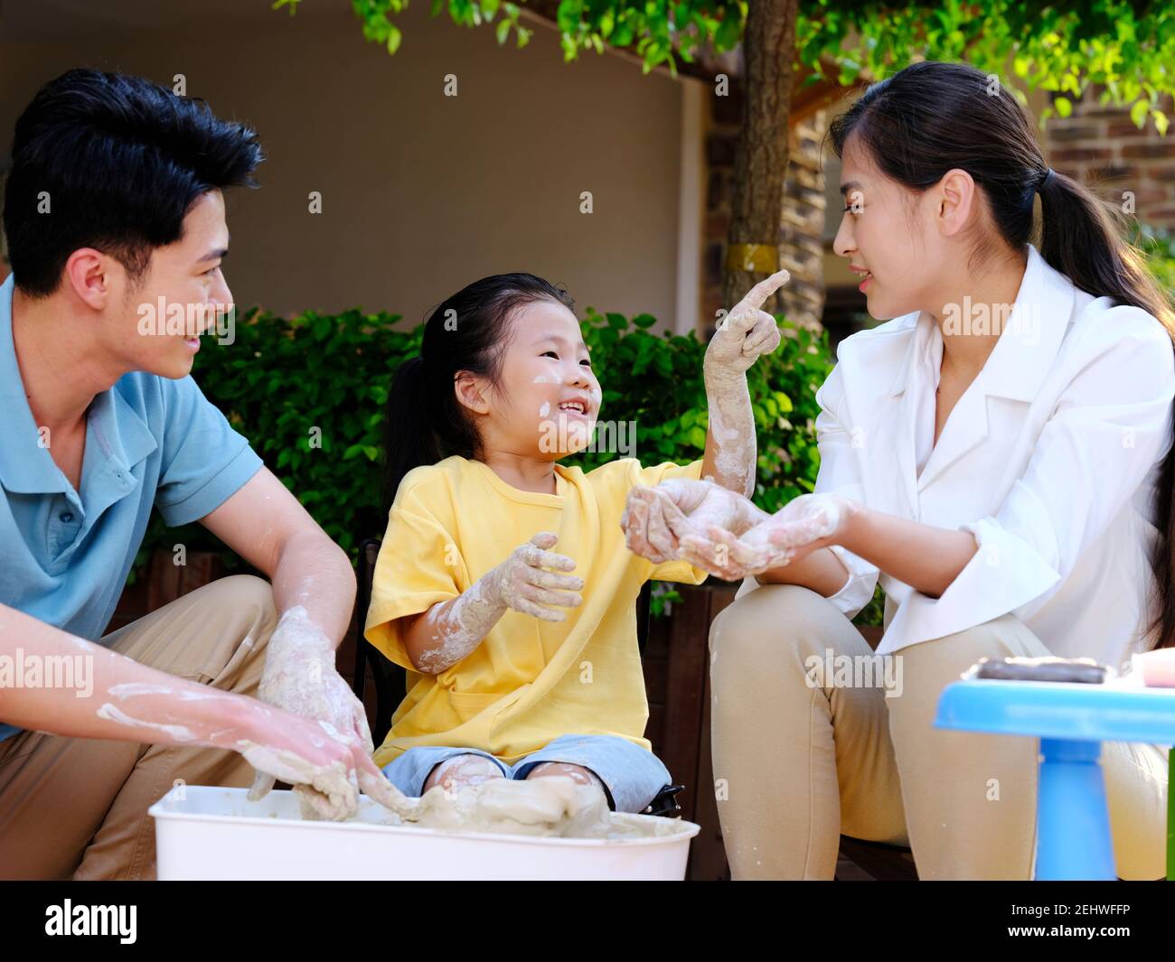 Happy family of three doing pottery together outdoors smiling Stock ...