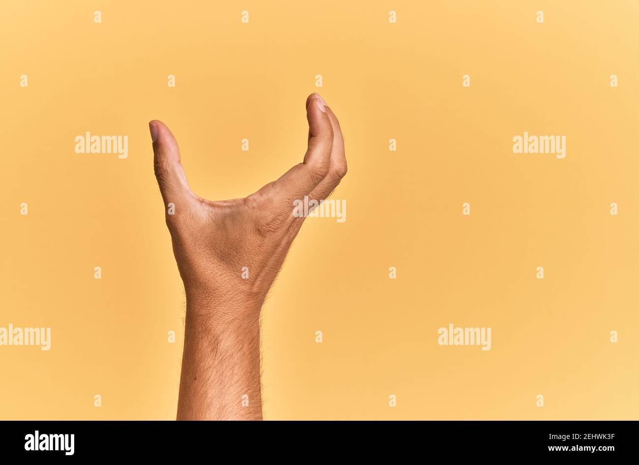 Arm and hand of caucasian man over yellow isolated background picking ...