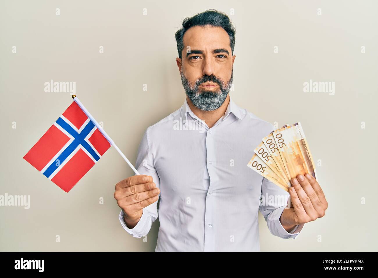 Middle age man with beard and grey hair holding norway flag and krone ...