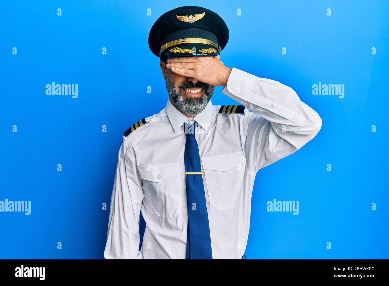 Middle age man with beard and grey hair wearing airplane pilot uniform ...