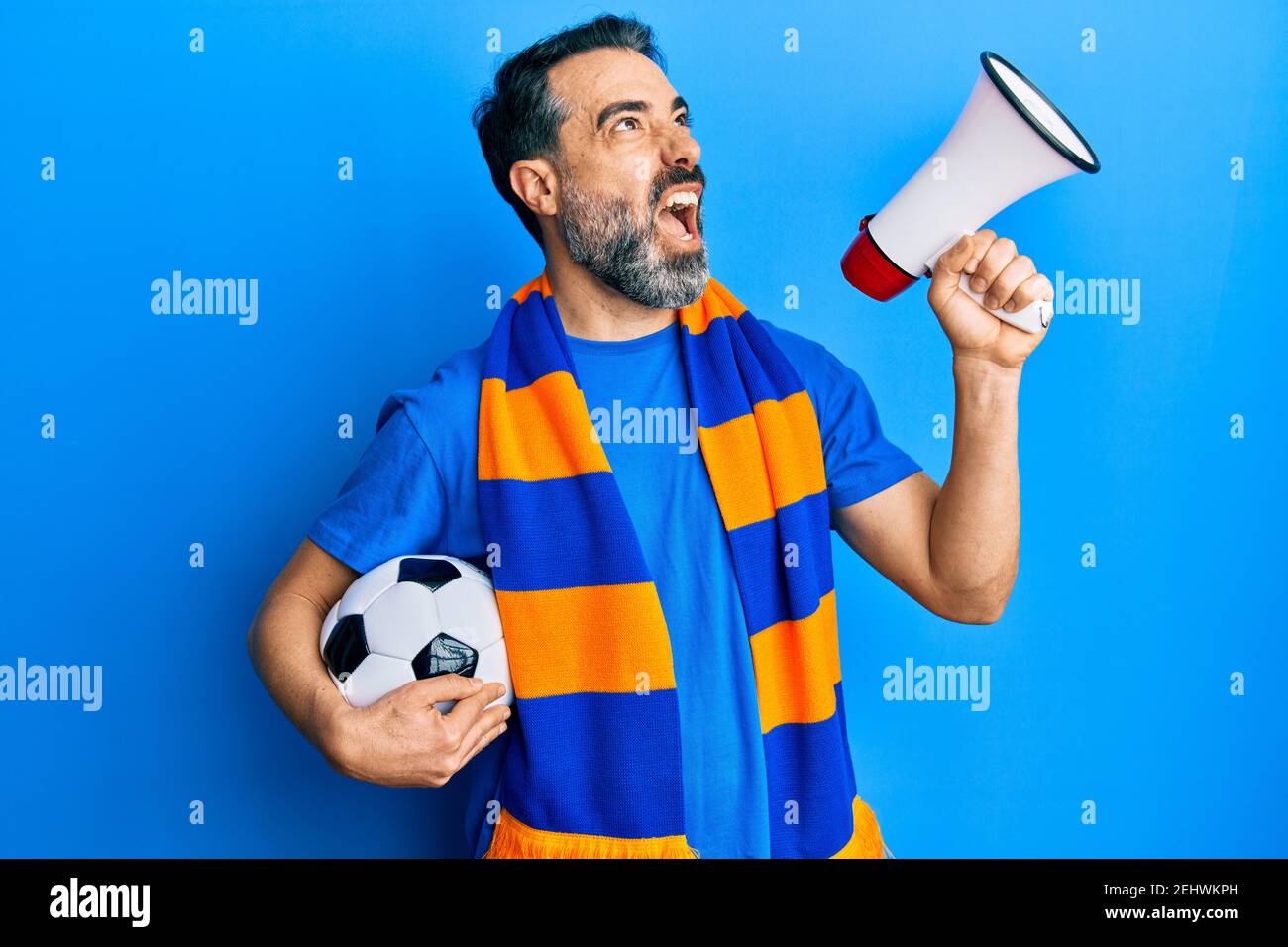 Middle age man with beard and grey hair football hooligan holding ball ...