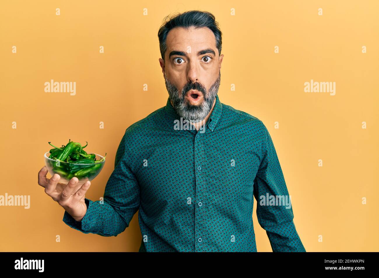 Middle age man with beard and grey hair holding green apples scared and ...