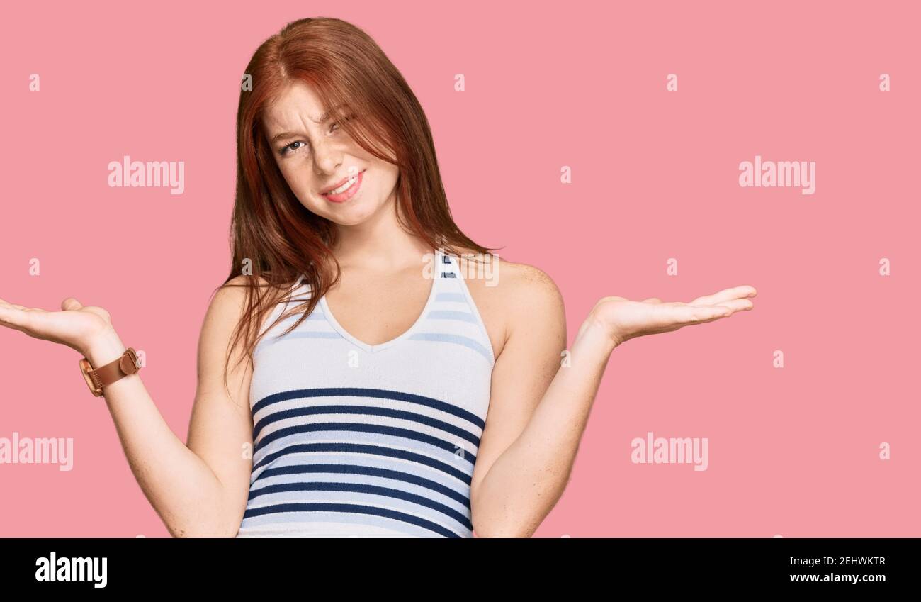 Young read head woman wearing casual clothes clueless and confused ...