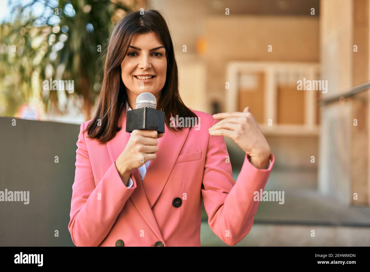 Middle age reporter woman holding microphone doing television speech ...