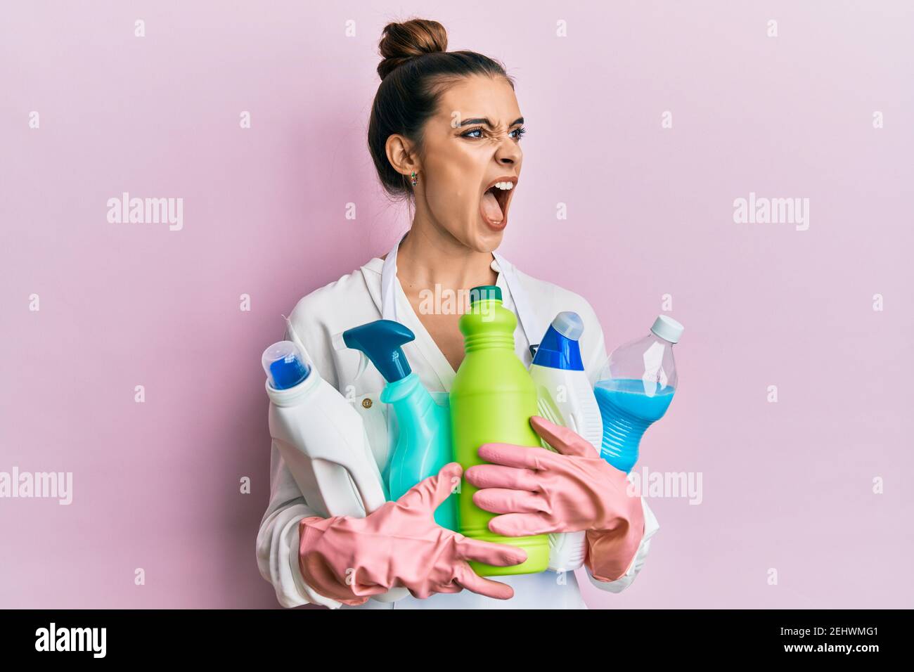 Beautiful brunette young woman wearing cleaner apron holding cleaning ...