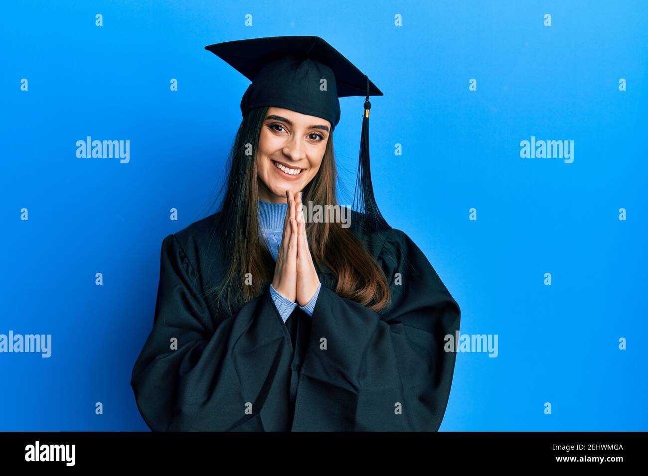 Beautiful brunette young woman wearing graduation cap and ceremony robe ...