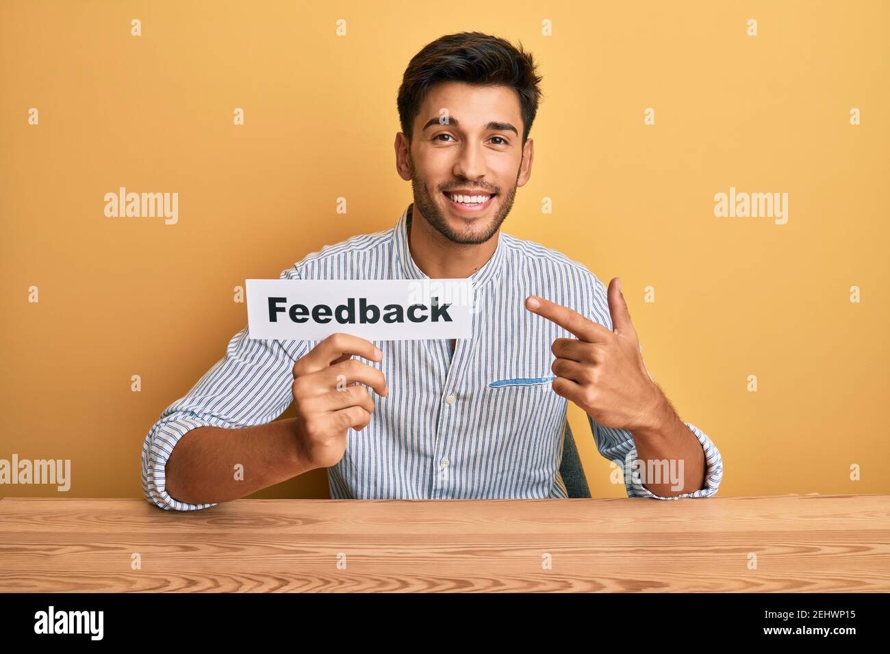 Young handsome man holding feedback paper for customer evaluation ...