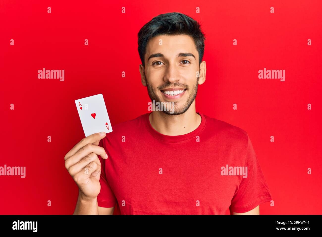Young handsome man holding ace poker card looking positive and happy ...