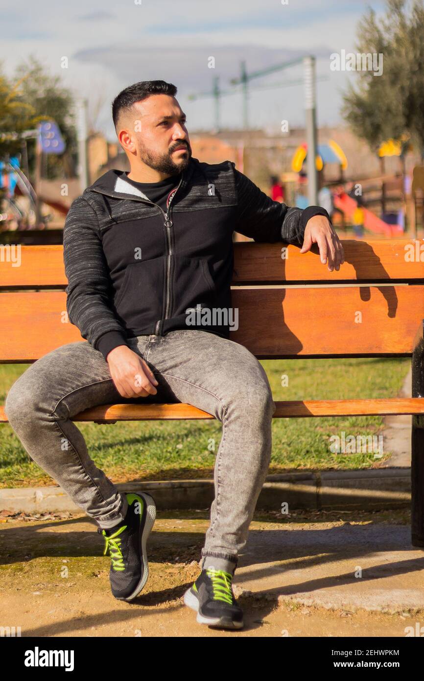 Vertical shot of a young male sitting on a bench in Stock Photo - Alamy