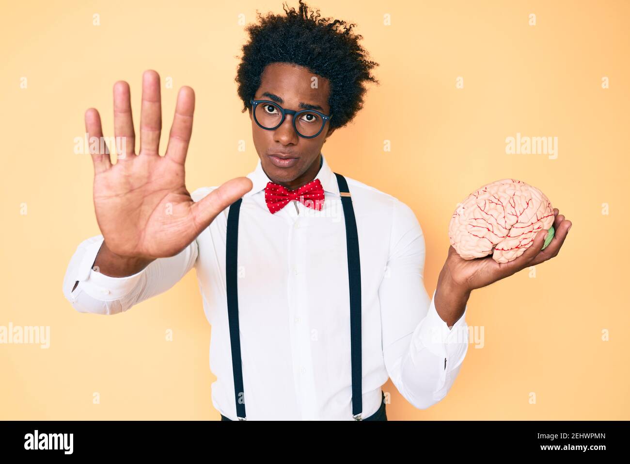 Handsome african american nerd man with afro hair holding brain with open hand doing stop sign ...