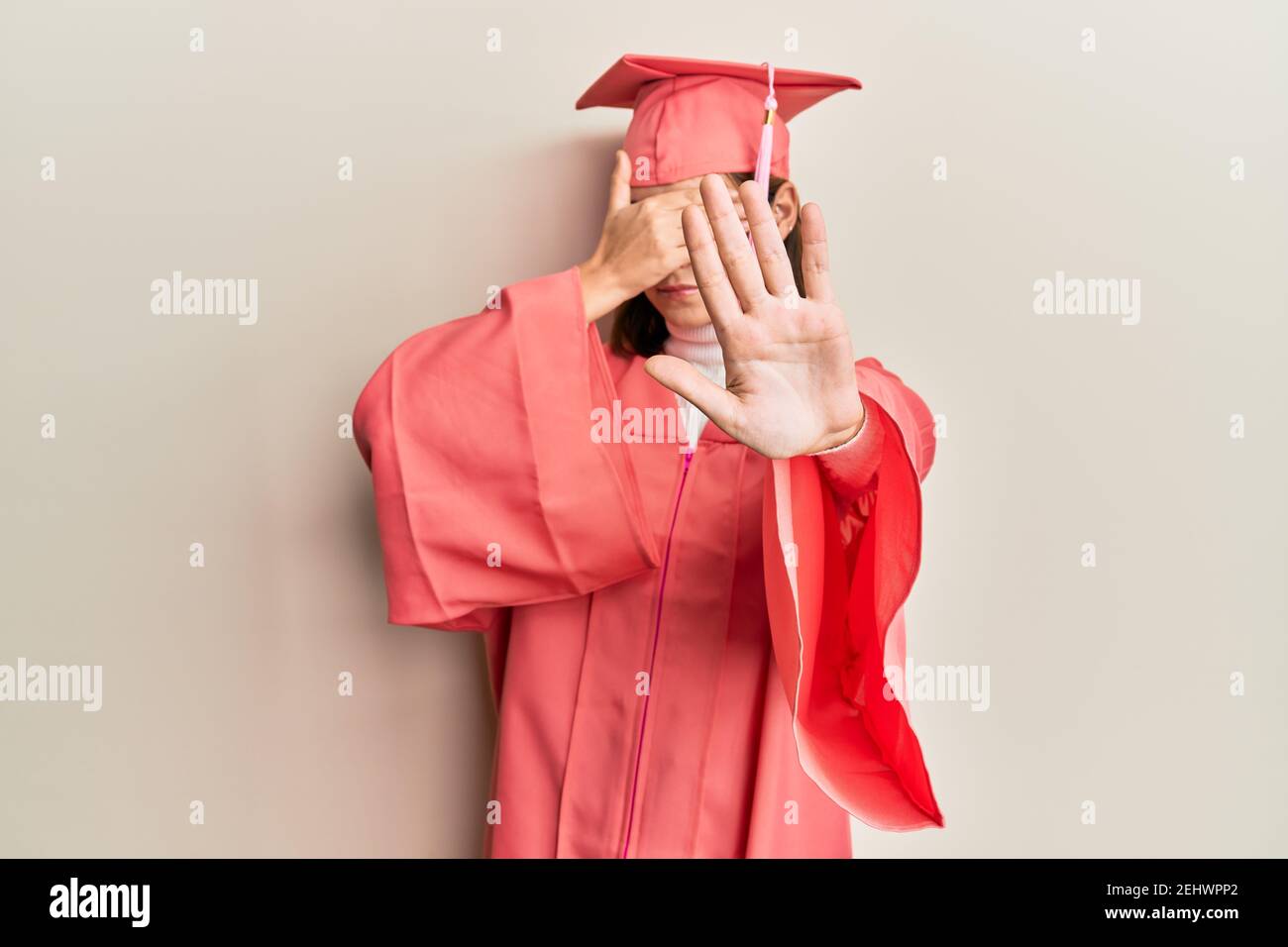 Young caucasian woman wearing graduation cap and ceremony robe covering ...