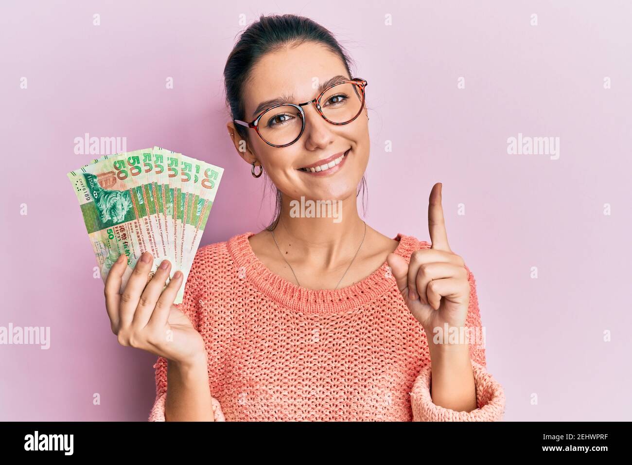 Young caucasian woman holding hong kong dollars banknotes smiling with ...
