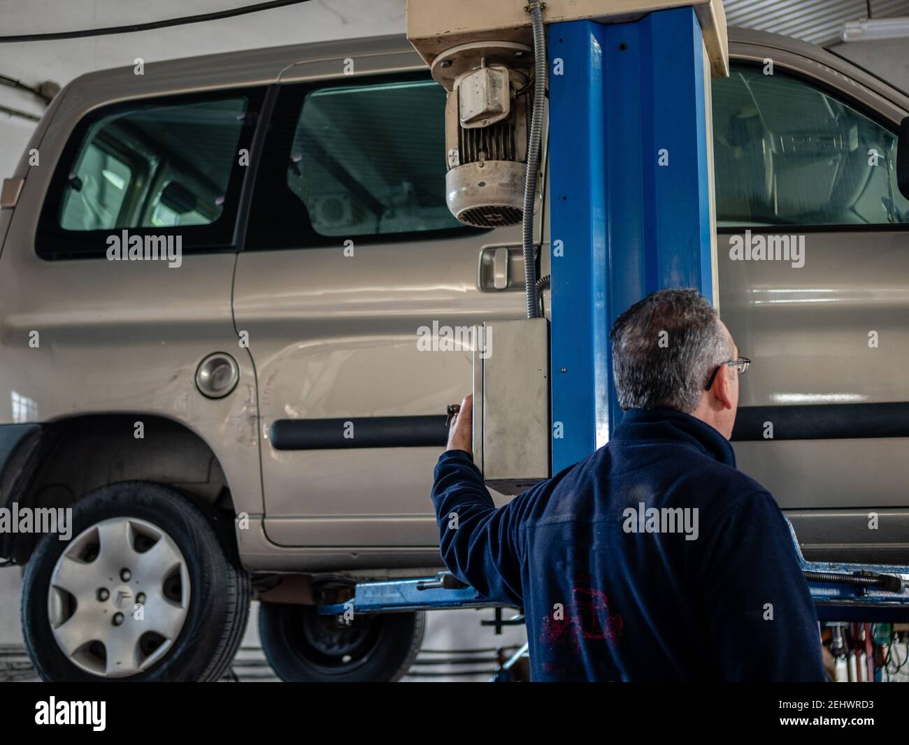 Mechanic in his workshop raising the car on the lift Stock Photo - Alamy