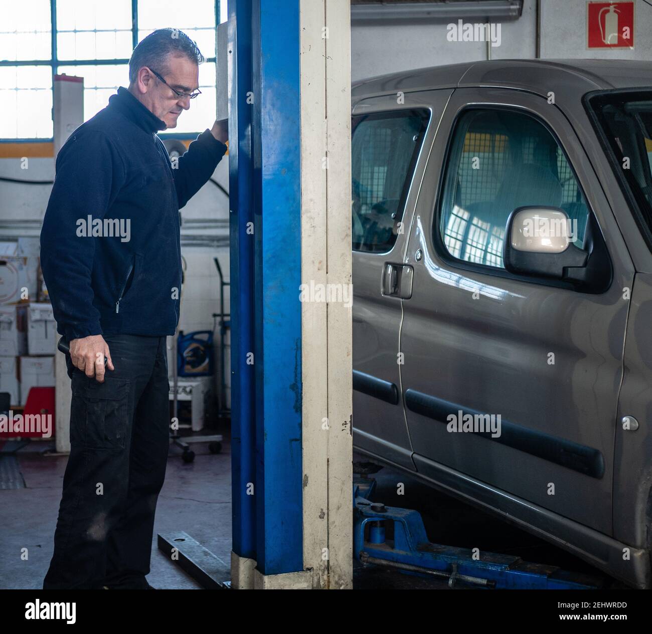 Mechanic in his workshop raising the car on the lift Stock Photo - Alamy