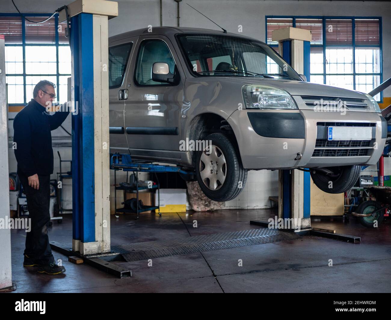 Mechanic in his workshop raising the car on the lift Stock Photo - Alamy