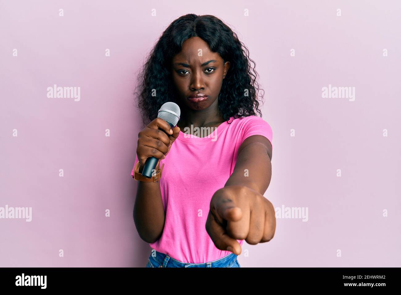 Beautiful african young woman singing song using microphone pointing to ...