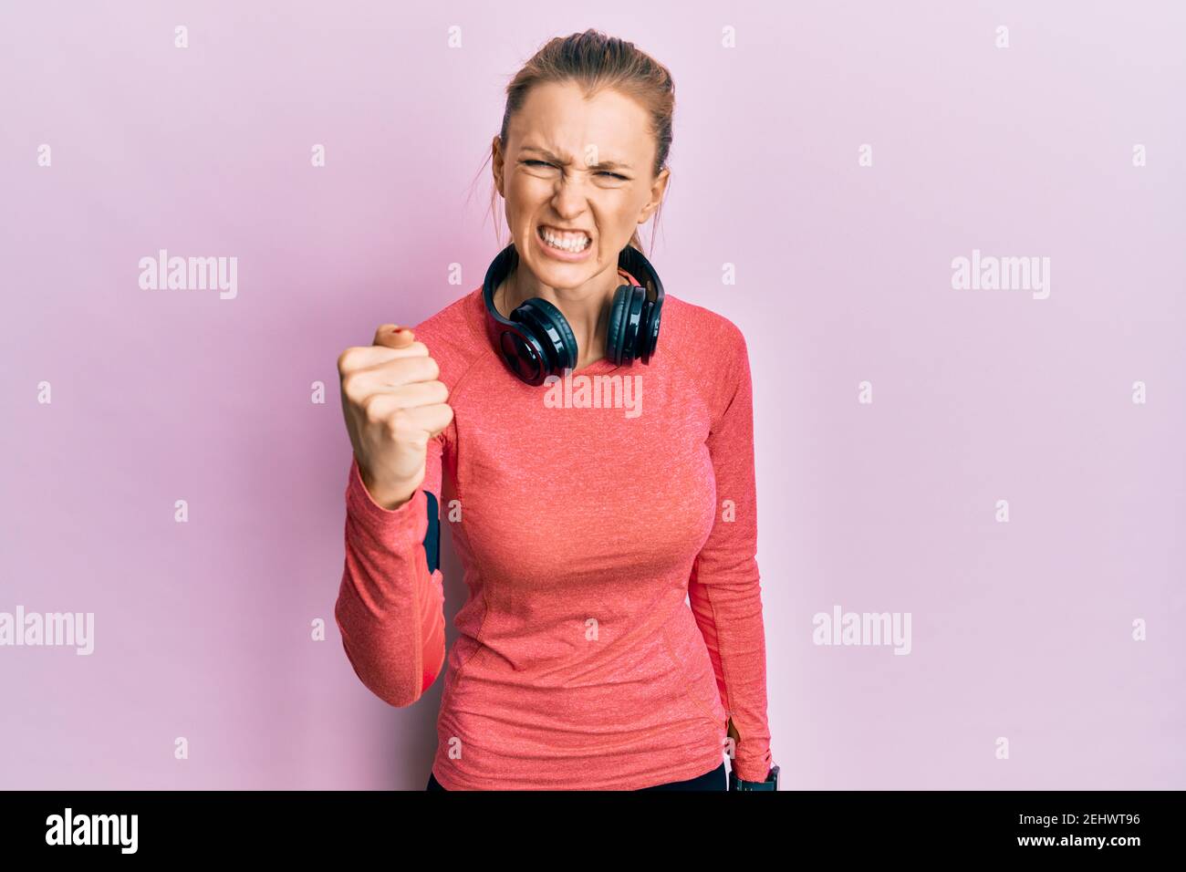 Beautiful caucasian woman wearing sportswear and arm band angry and mad ...
