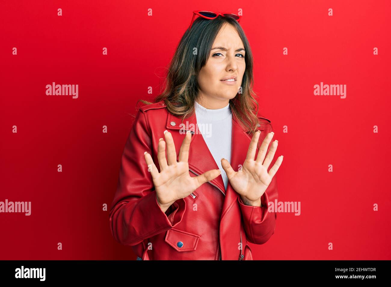Young brunette woman wearing red leather jacket disgusted expression ...