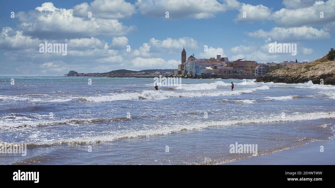 Wavy beach with people in waters on background of the coastal city ...