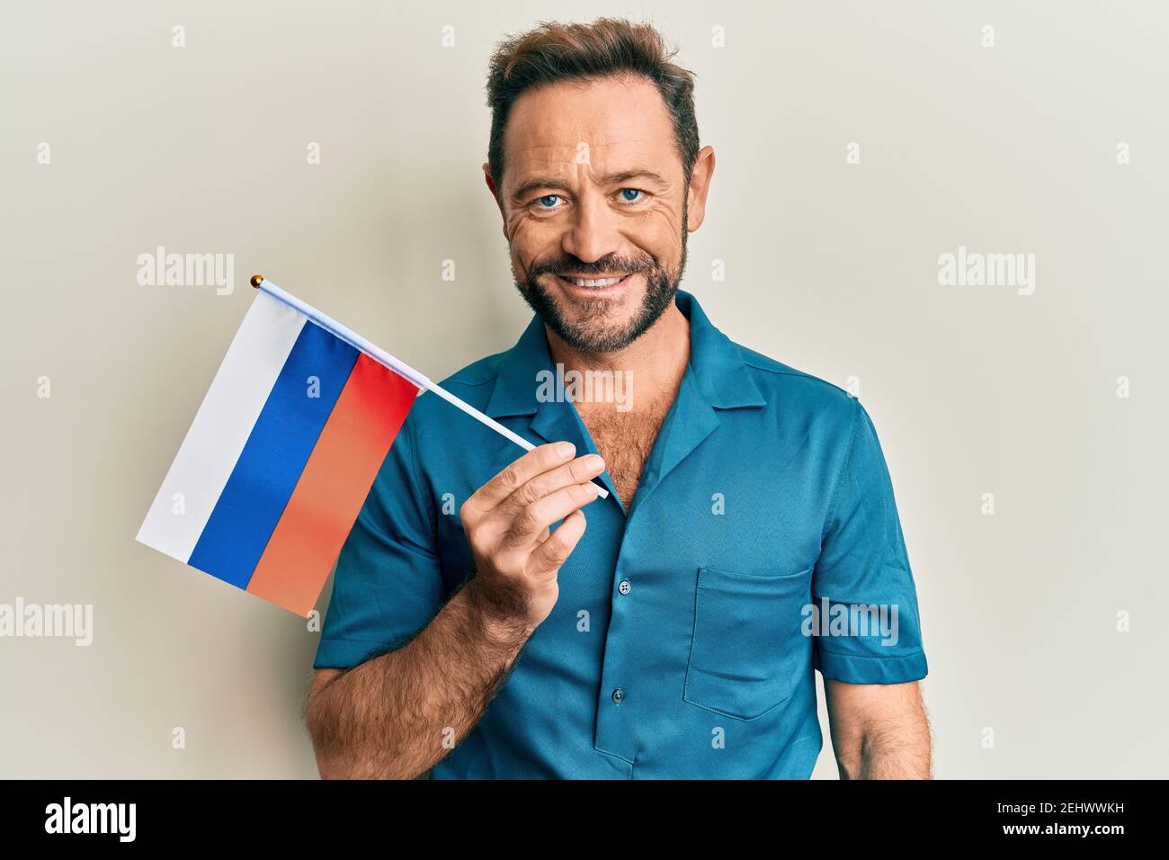 Middle age man holding russia flag looking positive and happy standing ...