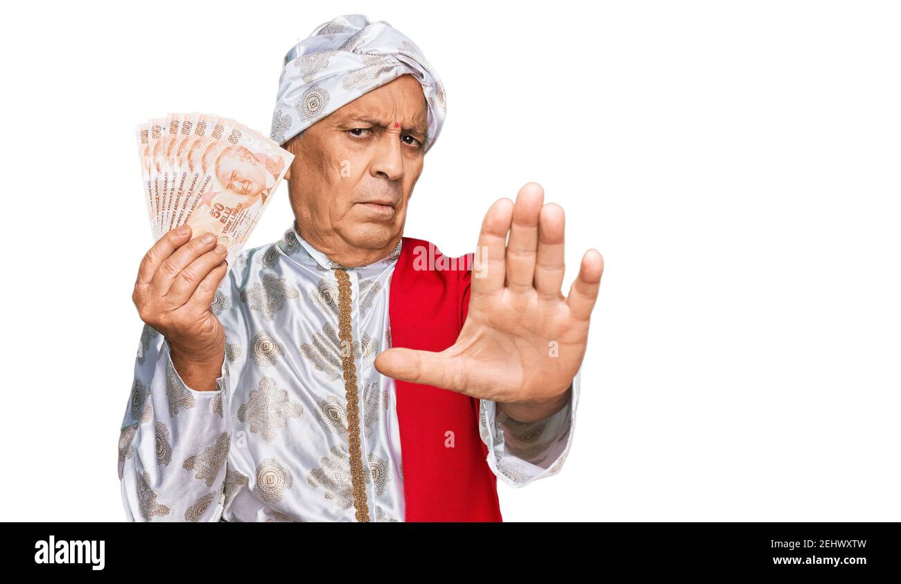 Senior hispanic man wearing sherwani costume holding 50 indian rupee ...