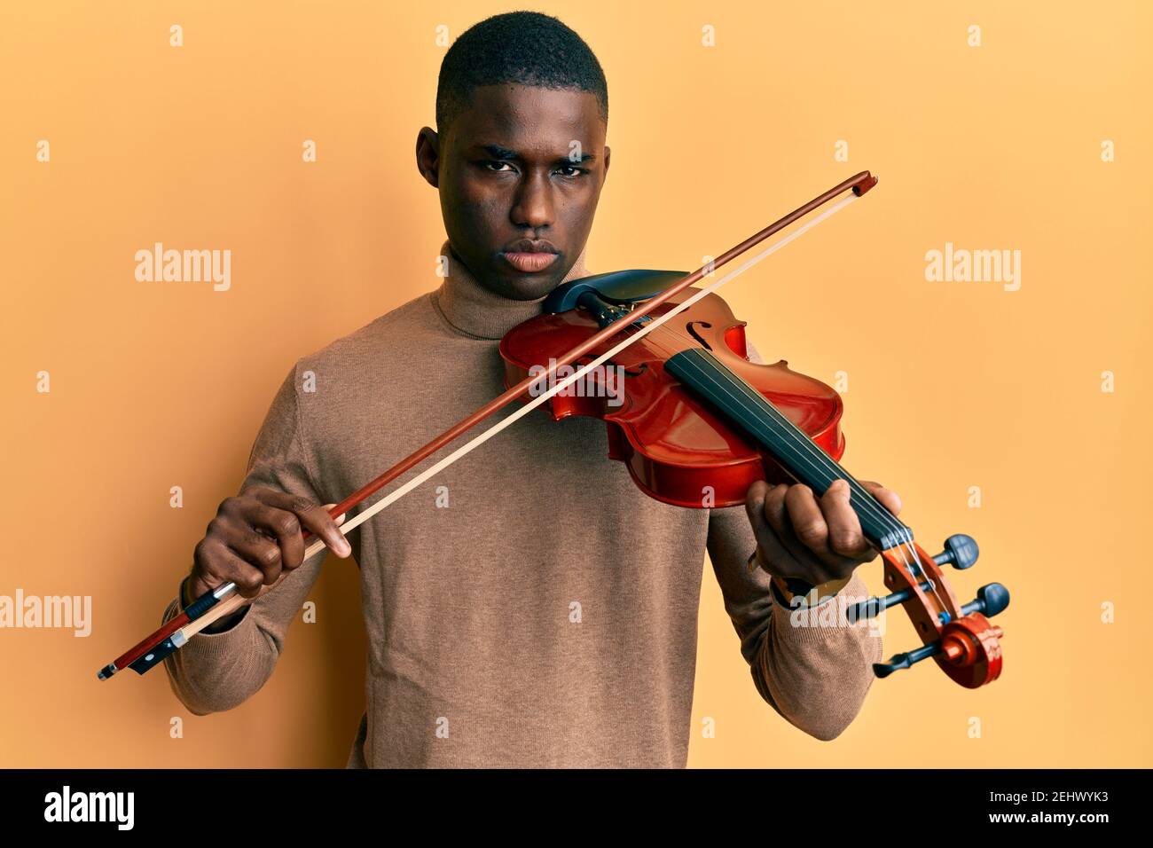 Young african american man playing violin depressed and worry for ...