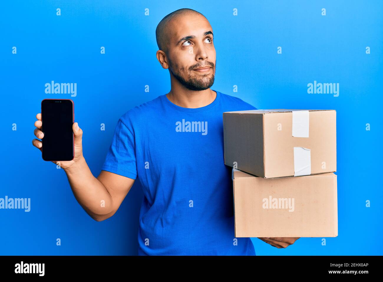 Hispanic adult man holding delivery packages and showing smartphone ...