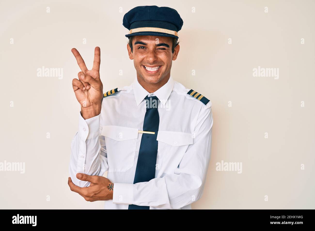 Young hispanic man wearing airplane pilot uniform smiling with happy ...