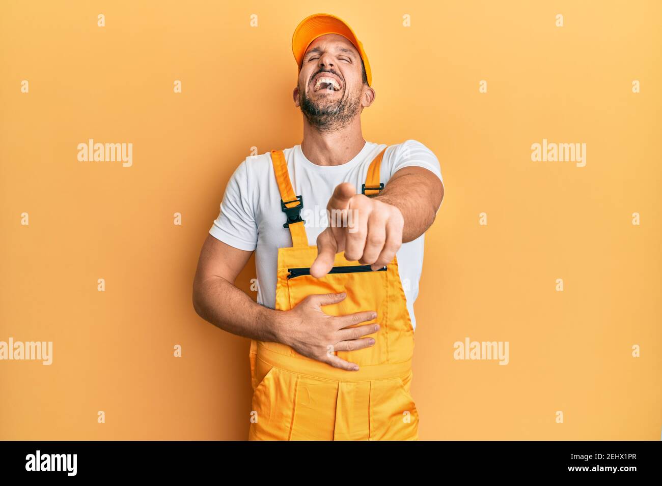 Young handsome man wearing handyman uniform over yellow background ...