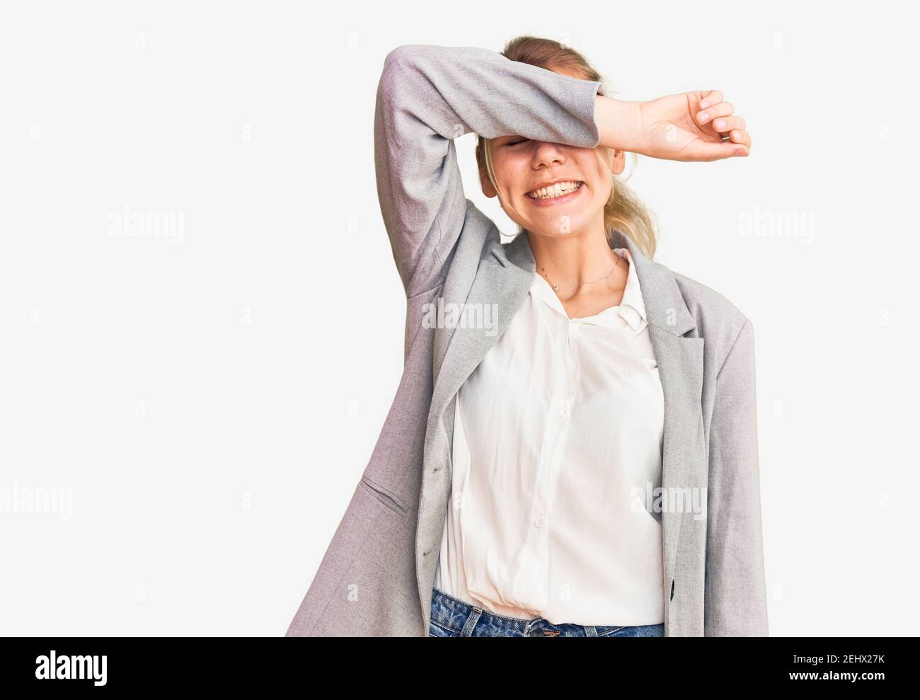 Young beautiful blonde woman wearing elegant jacket covering eyes with ...