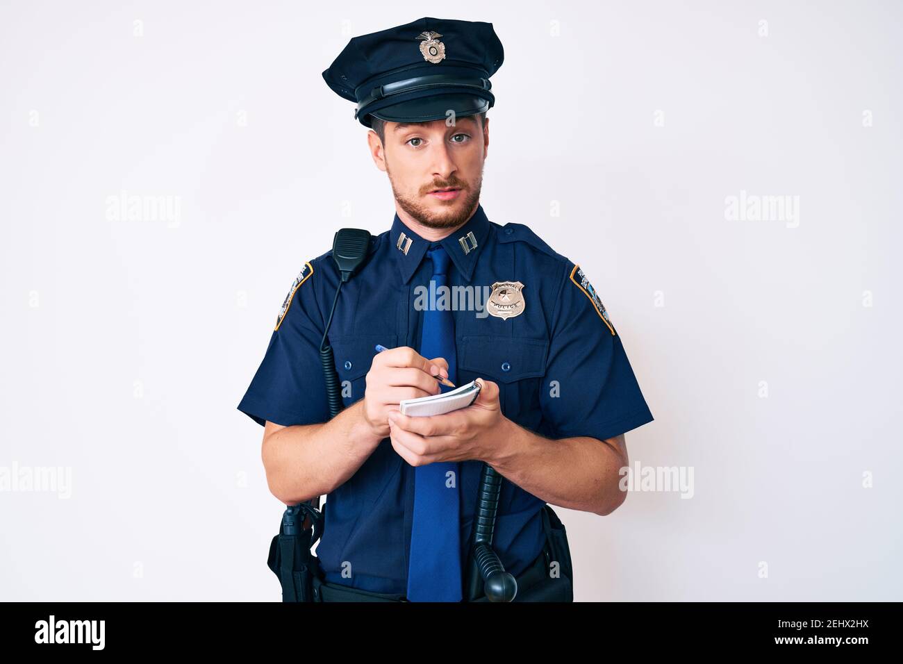 Young caucasian man wearing police uniform writing fine clueless and ...