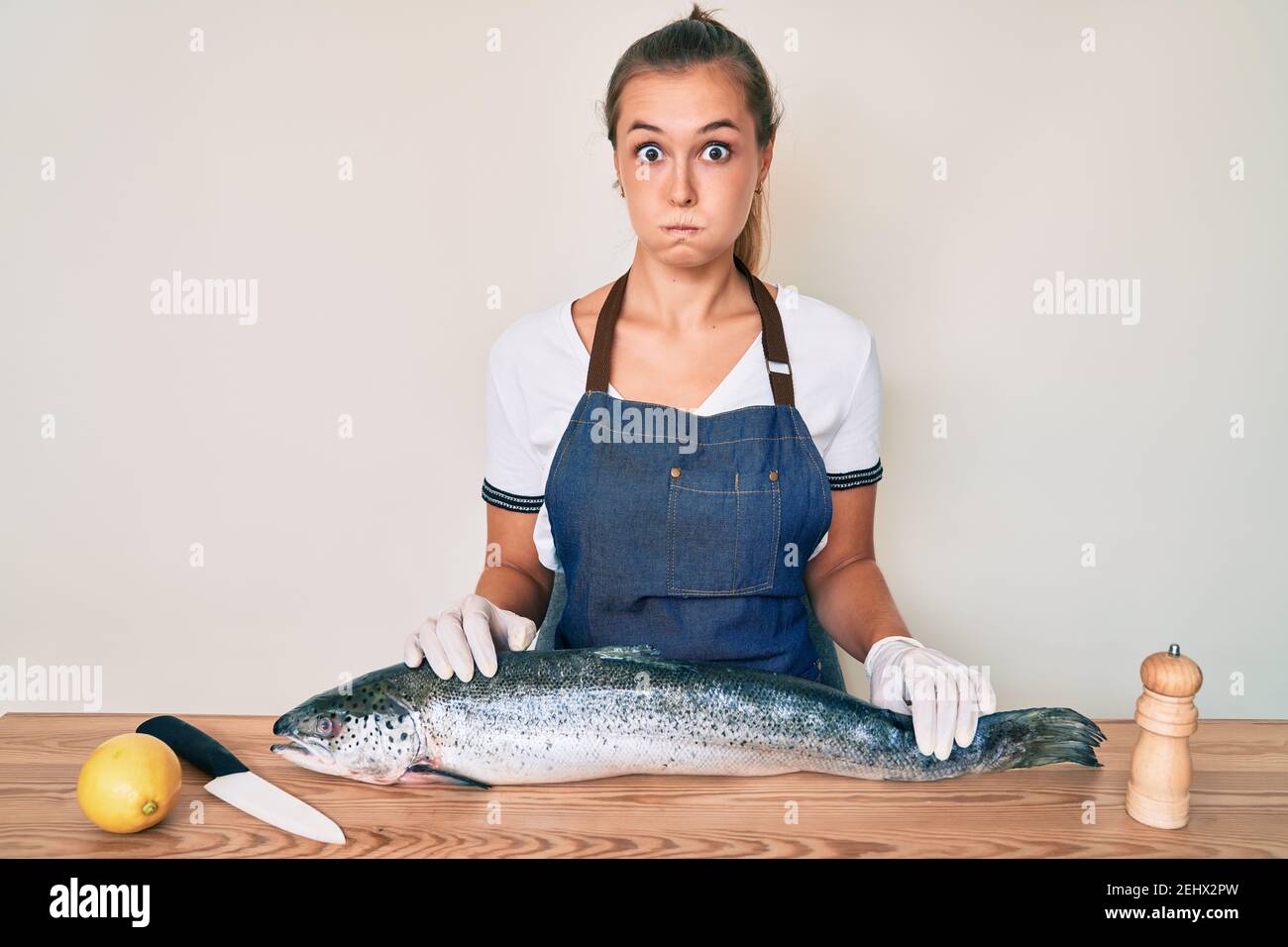 Beautiful caucasian woman fishmonger selling fresh raw salmon puffing ...