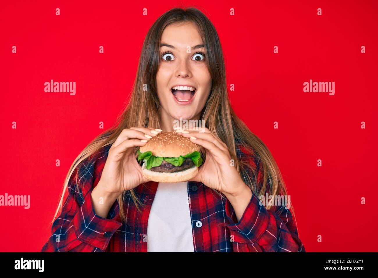 Beautiful caucasian woman eating a tasty classic burger celebrating ...
