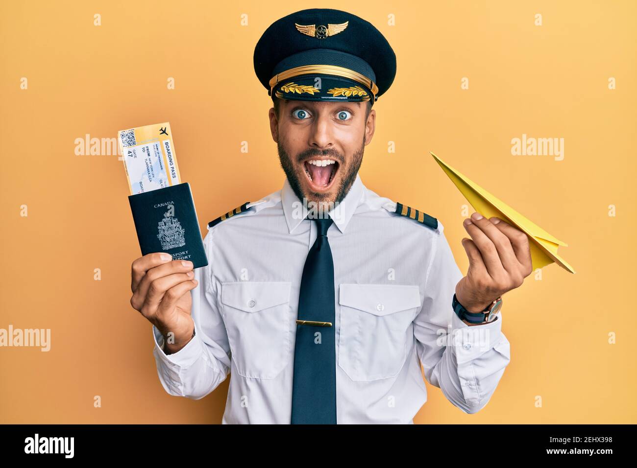 Handsome hispanic pilot man holding paper plane and passport ...