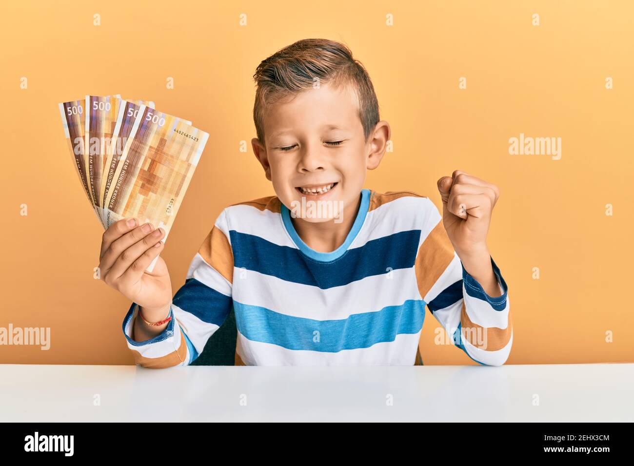 Adorable caucasian kid holding 500 norwegian krone banknotes sitting on ...