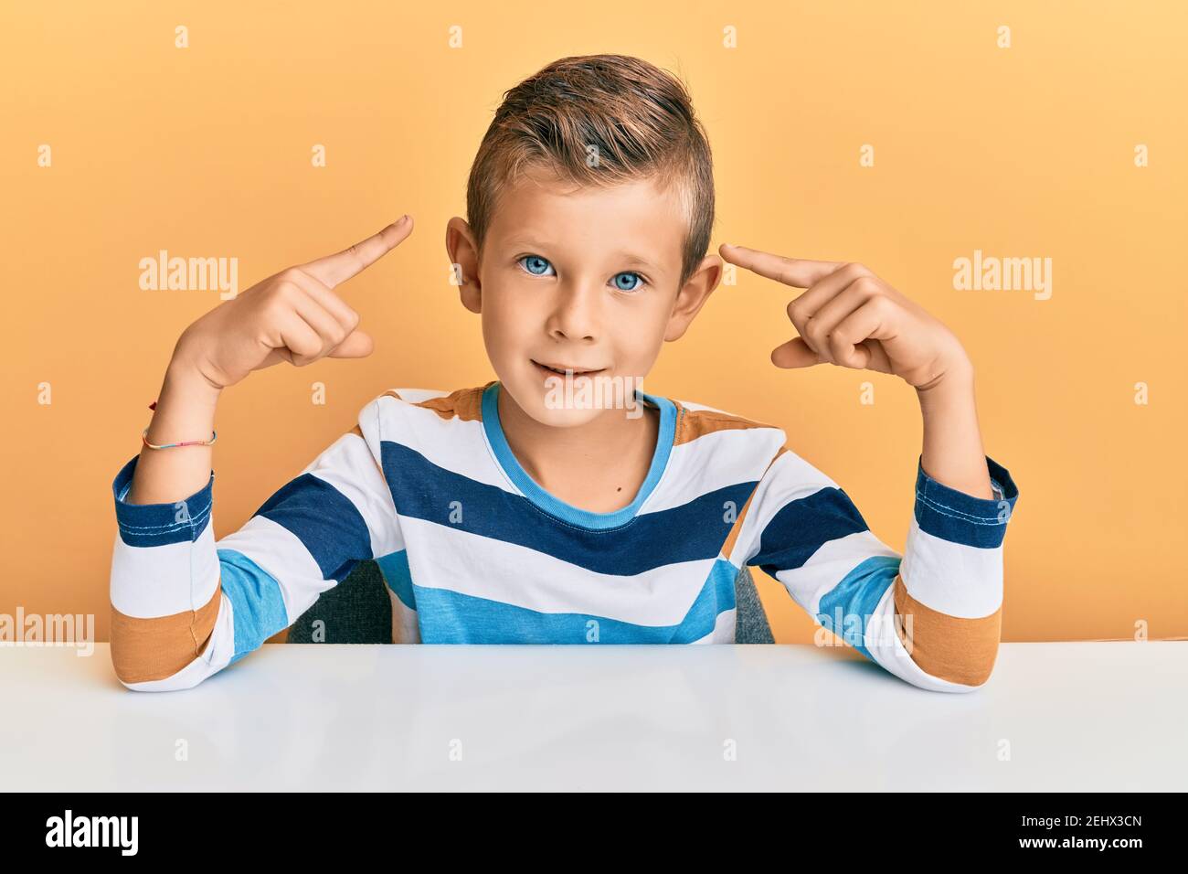 Adorable caucasian kid wearing casual clothes sitting on the table ...