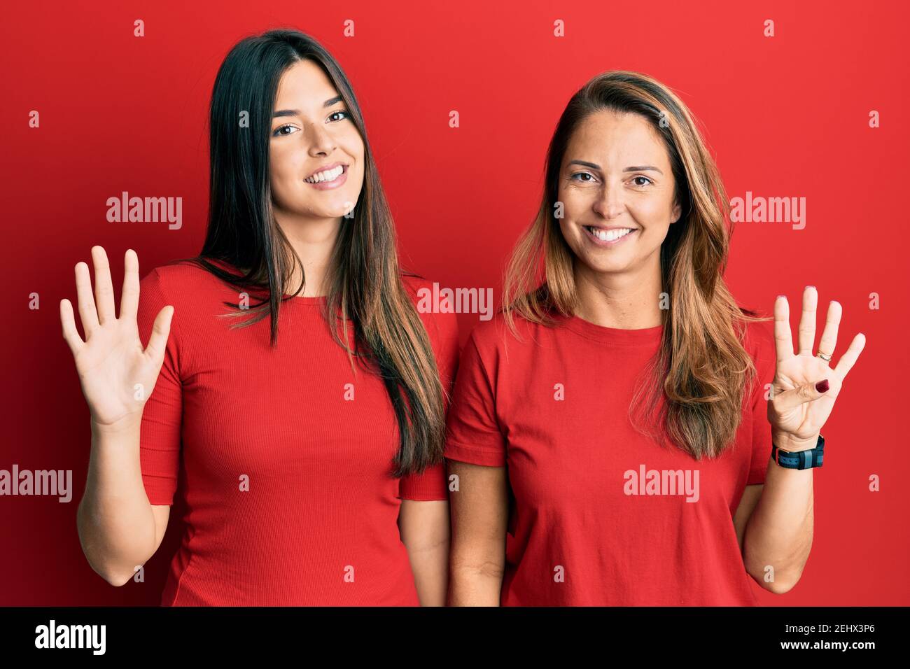 Hispanic family of mother and daughter wearing casual clothes over red ...