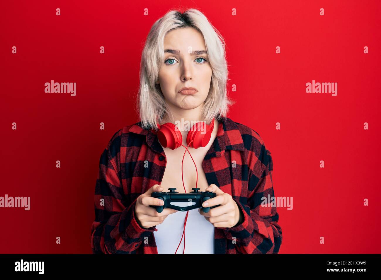 Young blonde girl playing video game holding controller depressed and ...
