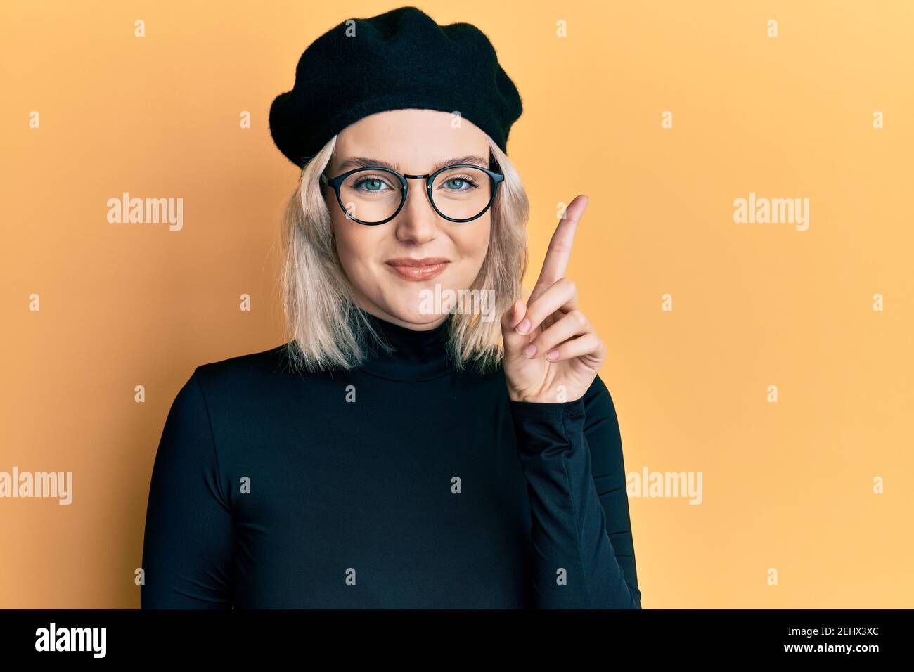 Young blonde girl wearing french look with beret showing and pointing ...