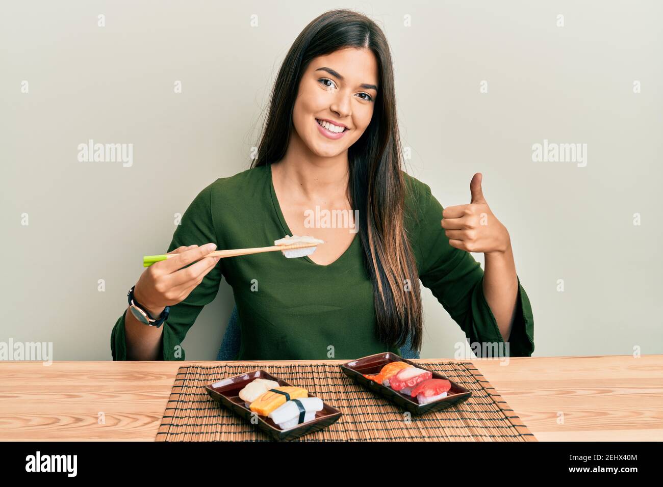 Young brunette woman eating sushi sitting on the table smiling happy ...